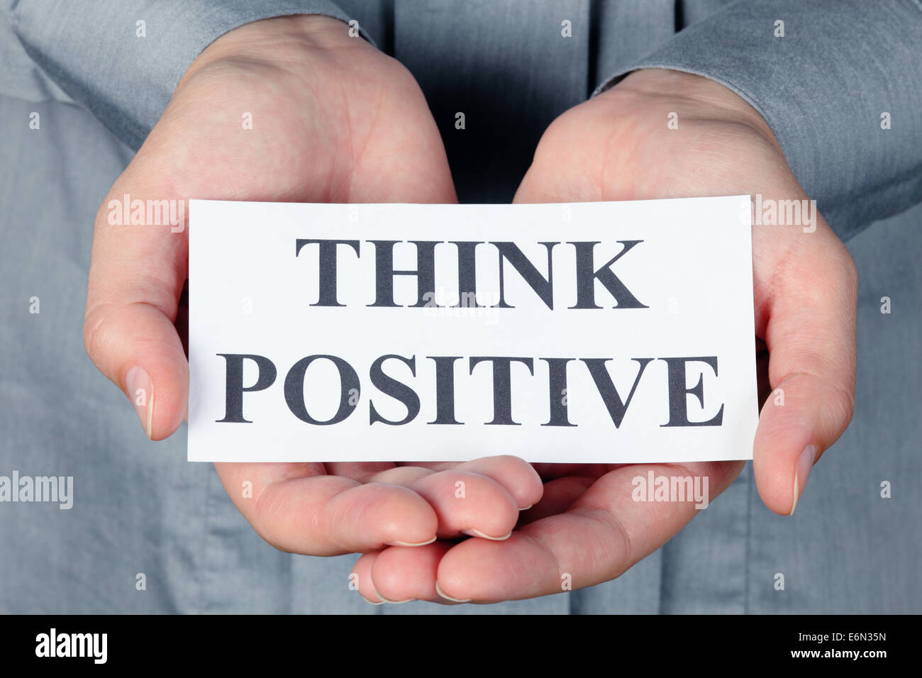 Piece of paper with the words "Think Positive" in the woman's palms ...