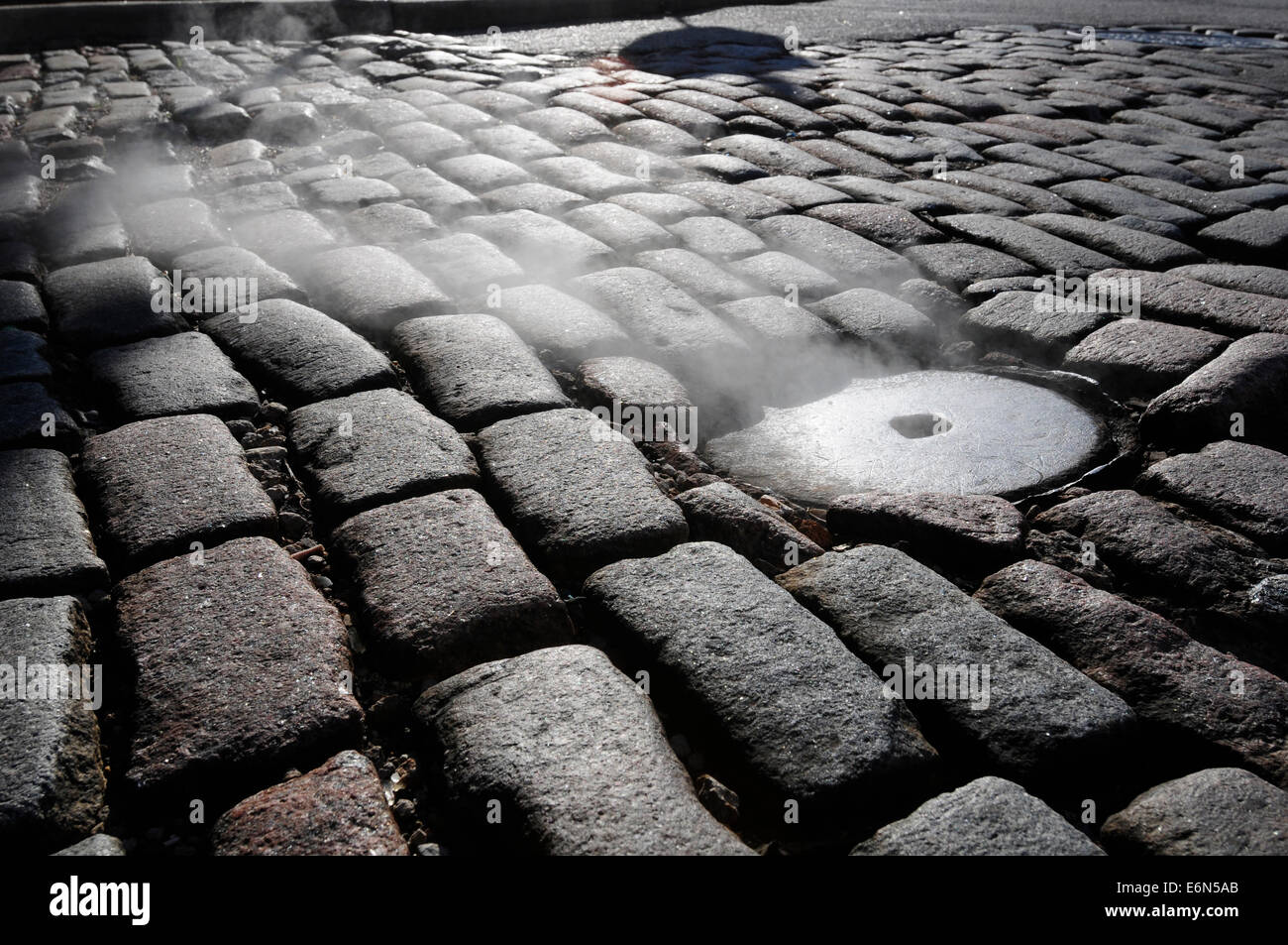A manhole cover venting steam on a brick street in St. Louis, Missouri ...