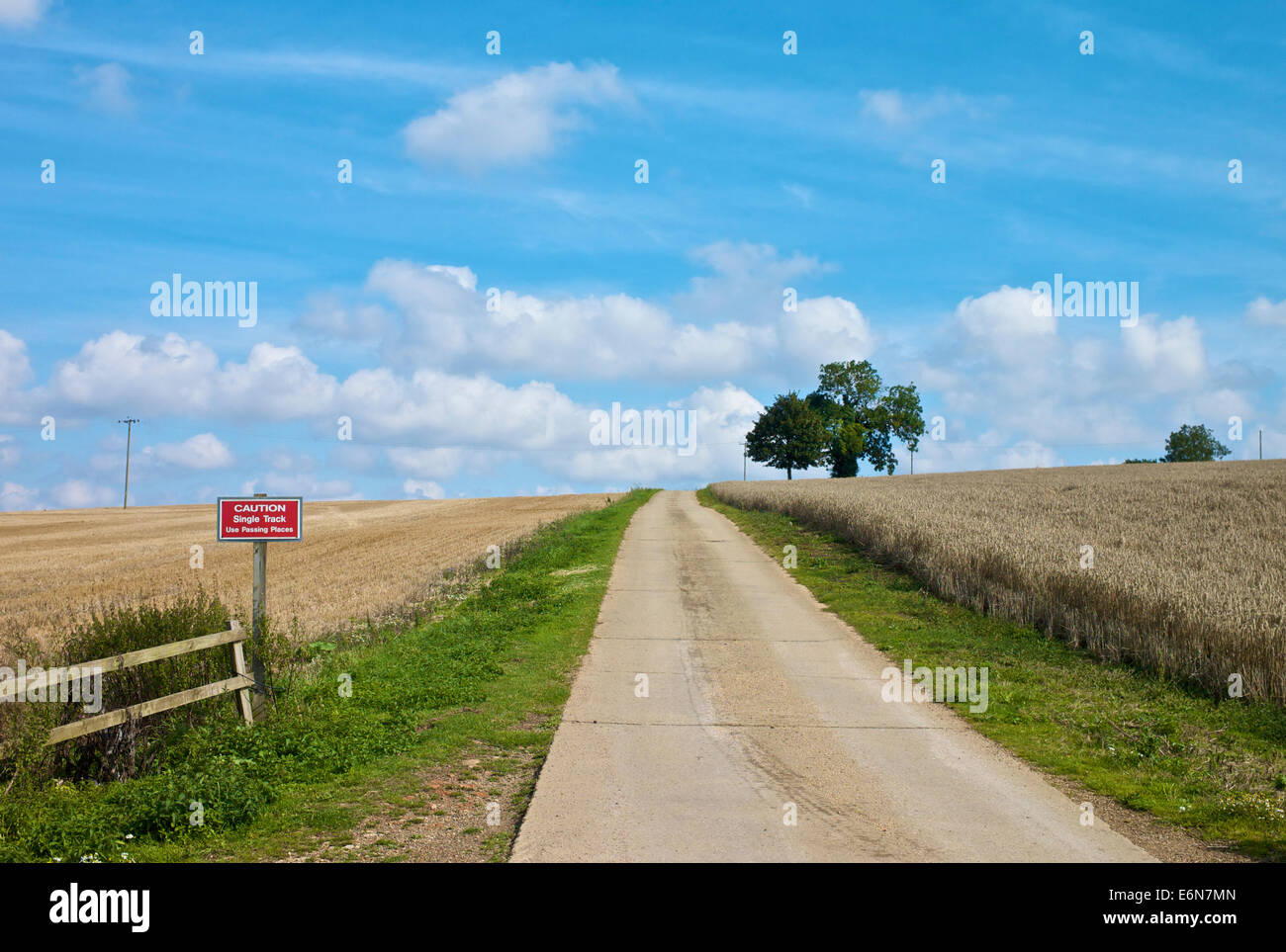 Farm track leading uphill through fields of crops. Red sign against ...