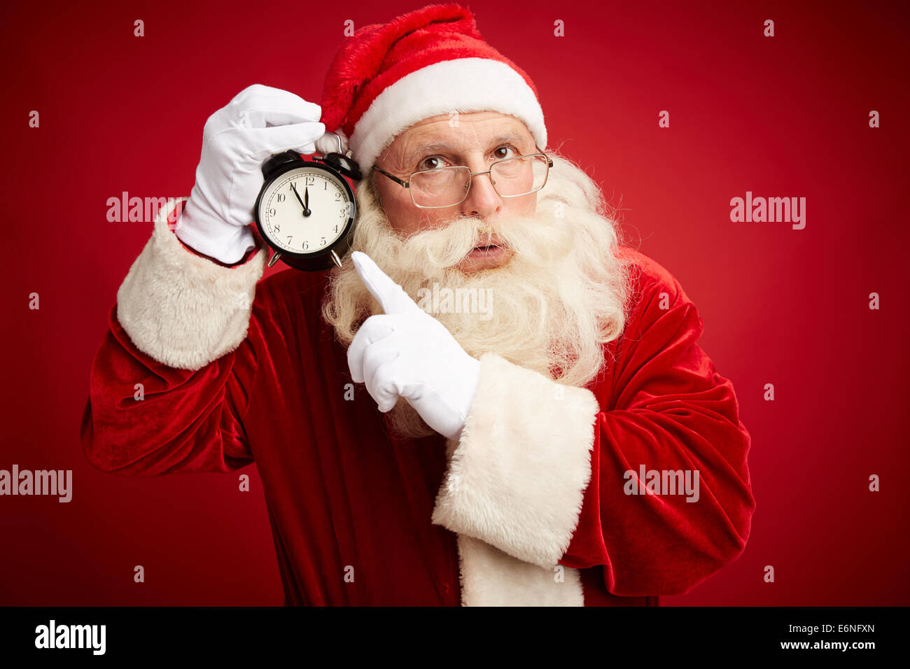 Pensive Santa Claus pointing at clock showing five minutes to midnight ...