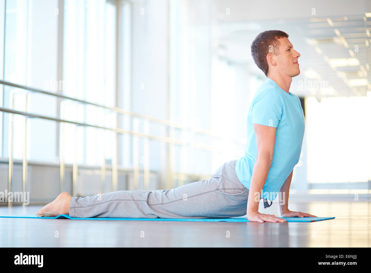 Healthy guy doing stretching exercise in gym Stock Photo - Alamy