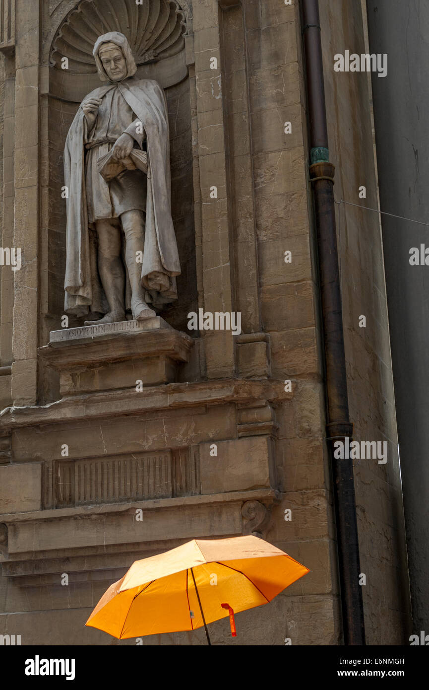 Stone figure of a man looking down at a yellow umbrella Stock Photo - Alamy