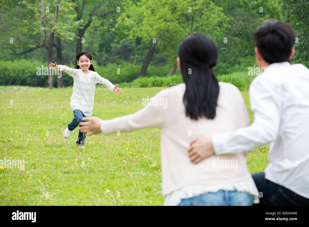 Happy girl running to hug her parents Stock Photo - Alamy