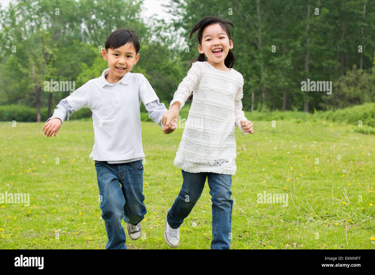 Happy children holding hands running on the grass Stock Photo - Alamy