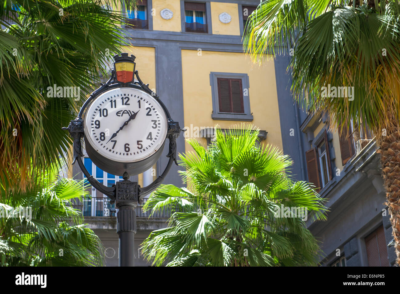 Large clock mounted onto a ornate metal lamp post with palm trees in a ...