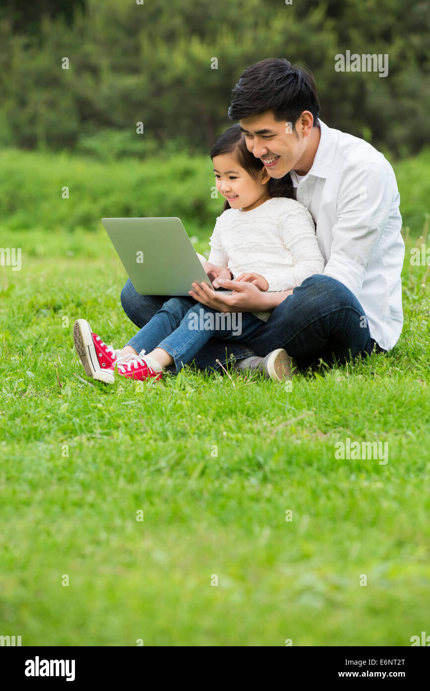 Father and daughter using laptop on the grass Stock Photo - Alamy