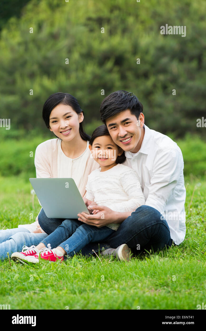 Happy family using laptop on the grass Stock Photo - Alamy