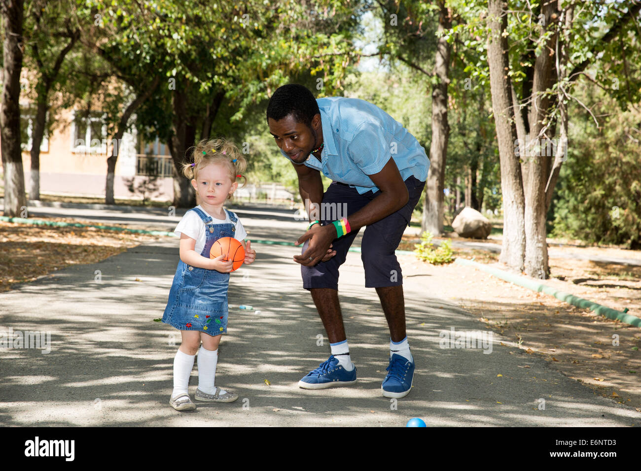 Young African American god father with little girl playing football on ...
