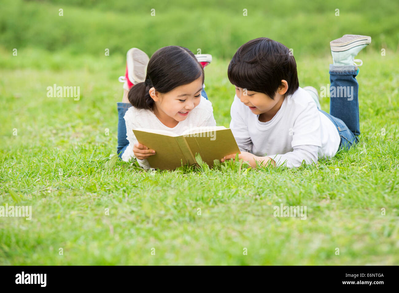 Boy and girl reading on the grass Stock Photo - Alamy