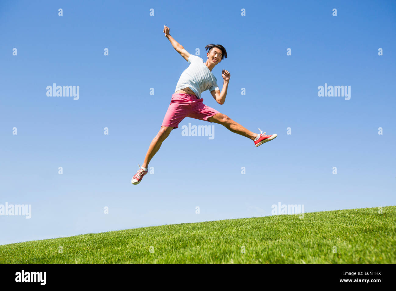 Cheerful young man jumping on grass Stock Photo - Alamy