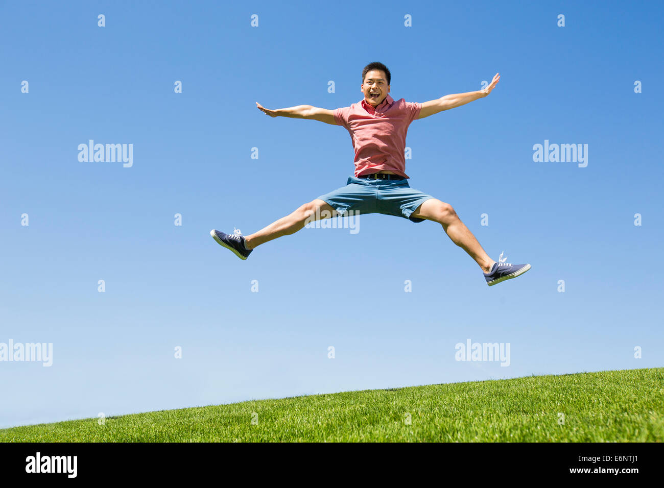 Cheerful young man jumping on grass Stock Photo - Alamy