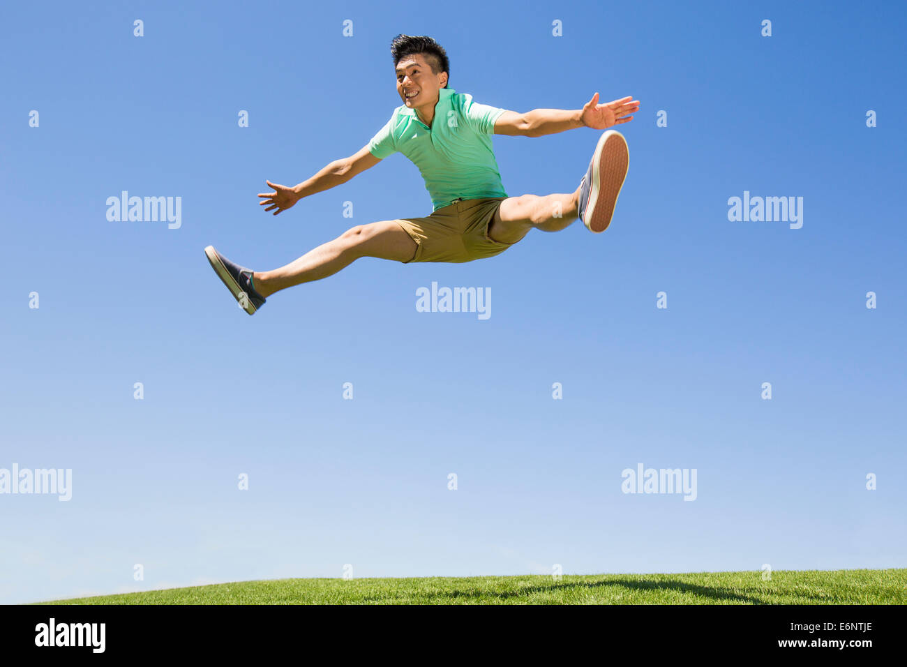 Cheerful young man jumping on grass Stock Photo - Alamy