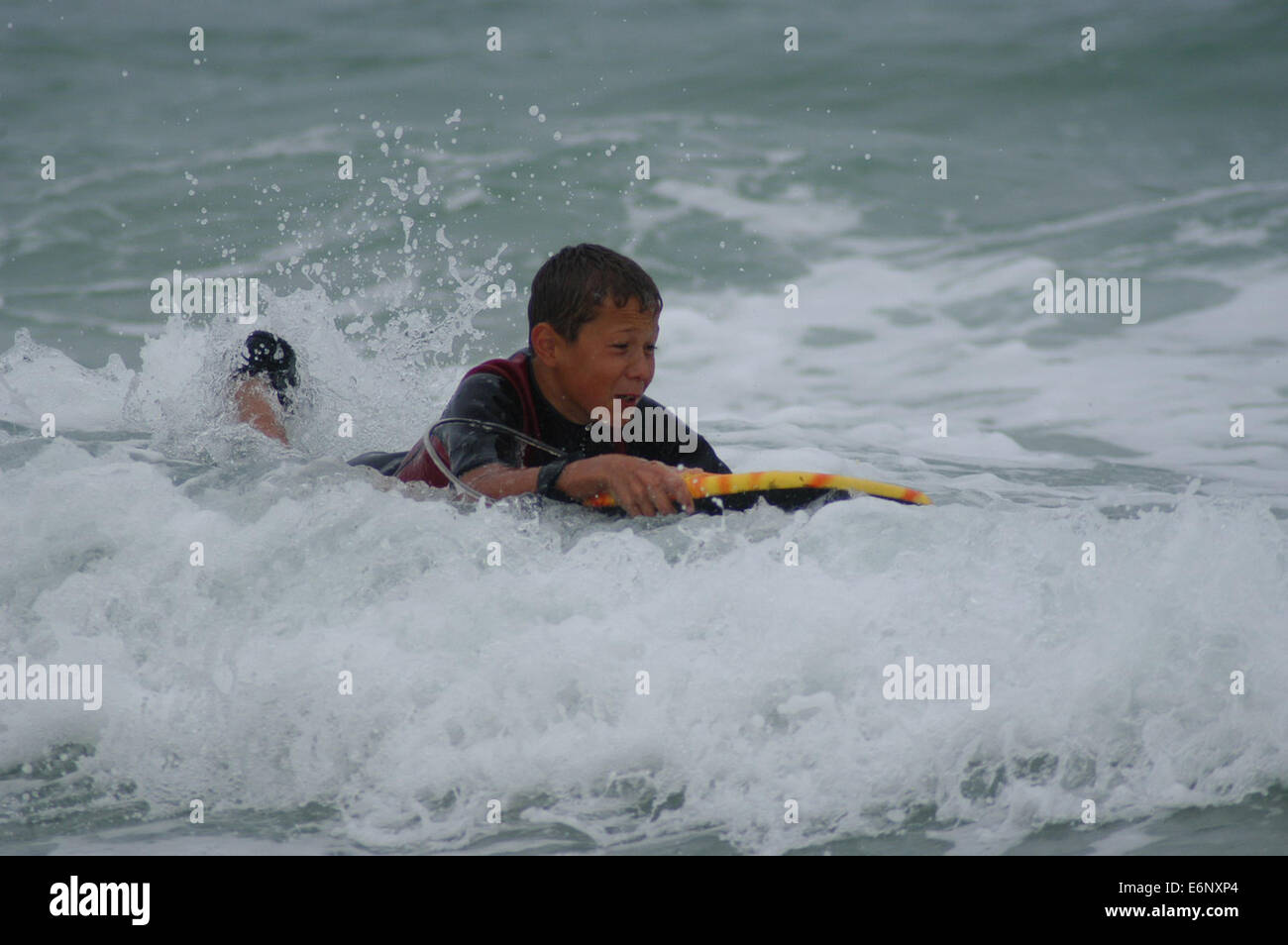 Young male teenager surfing on a bodyboard in the sea with a wave ...