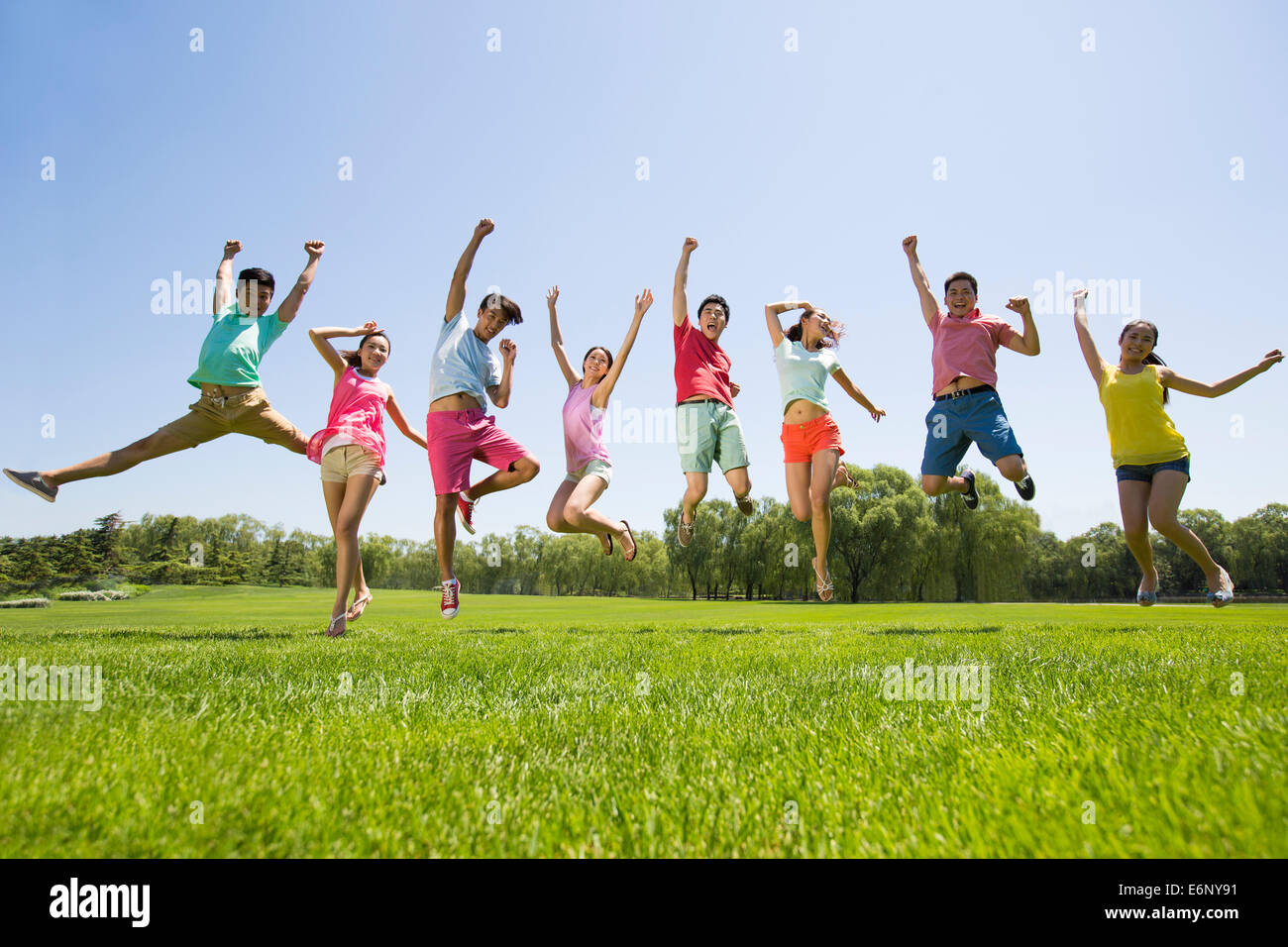Cheerful young adults jumping on grass Stock Photo - Alamy