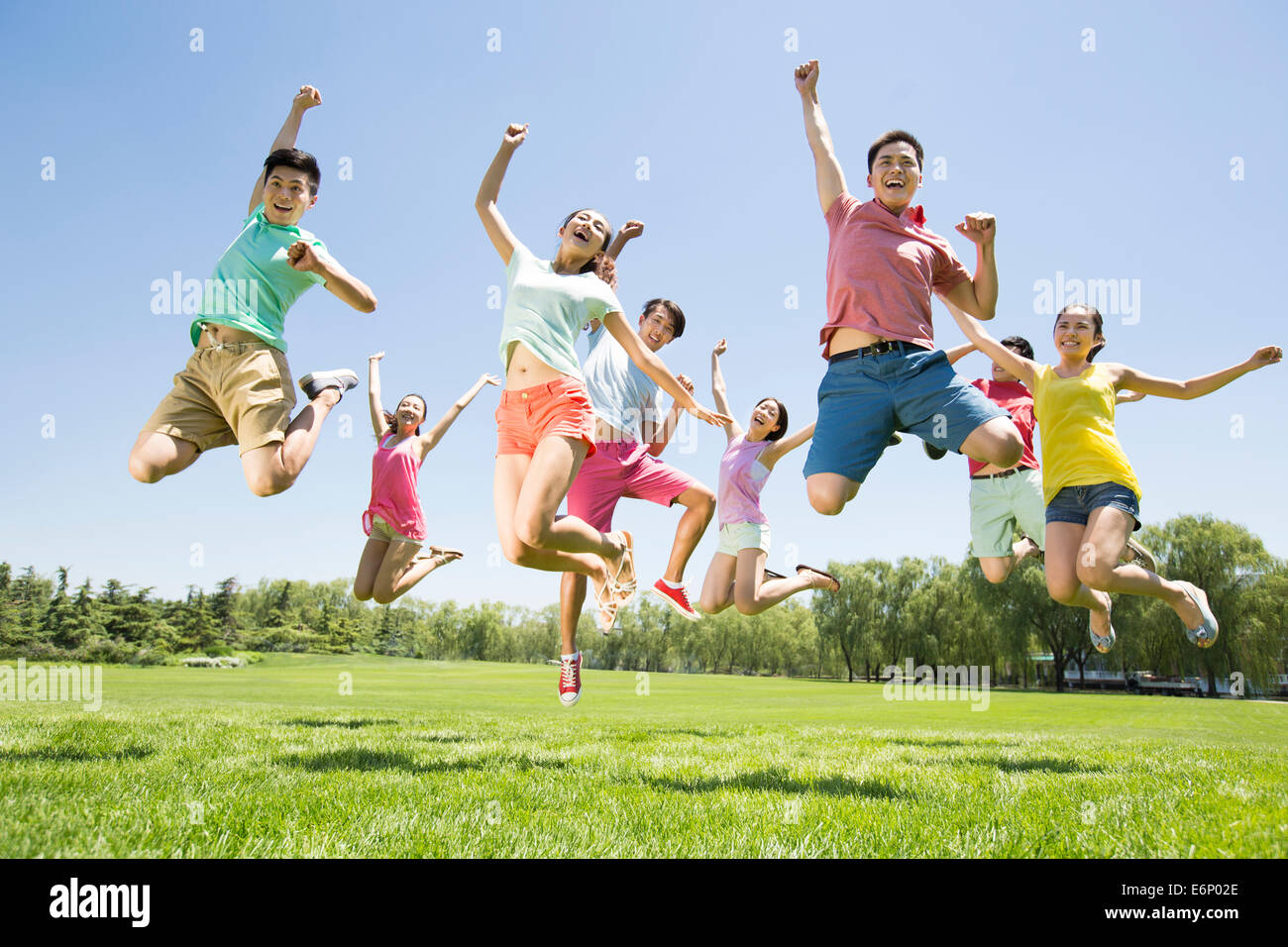 Cheerful young adults jumping on grass Stock Photo - Alamy