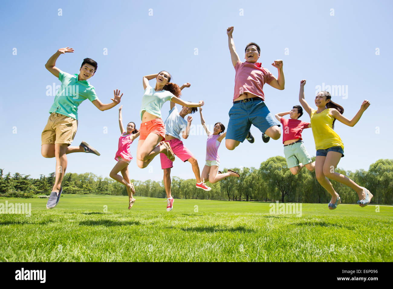 Cheerful young adults jumping on grass Stock Photo - Alamy
