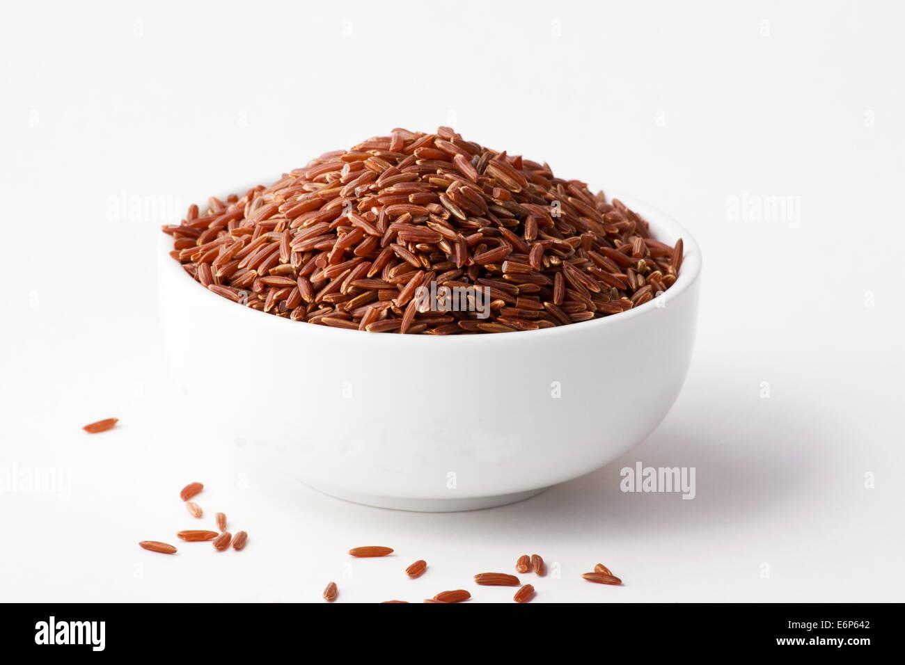 Red rice in a white bowl on white background Stock Photo - Alamy