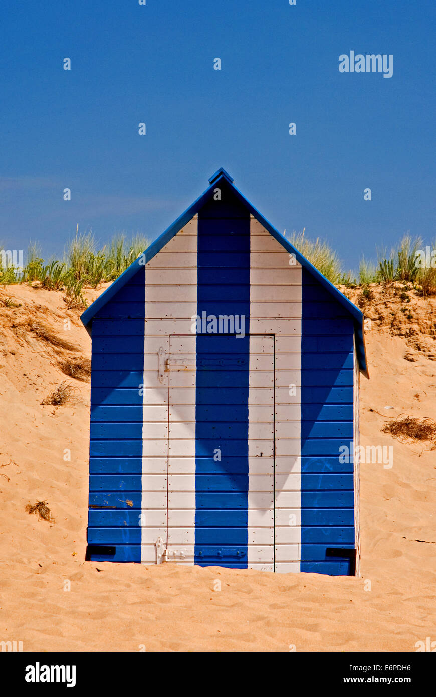 A blue and white striped beach hut on the beach Stock Photo - Alamy