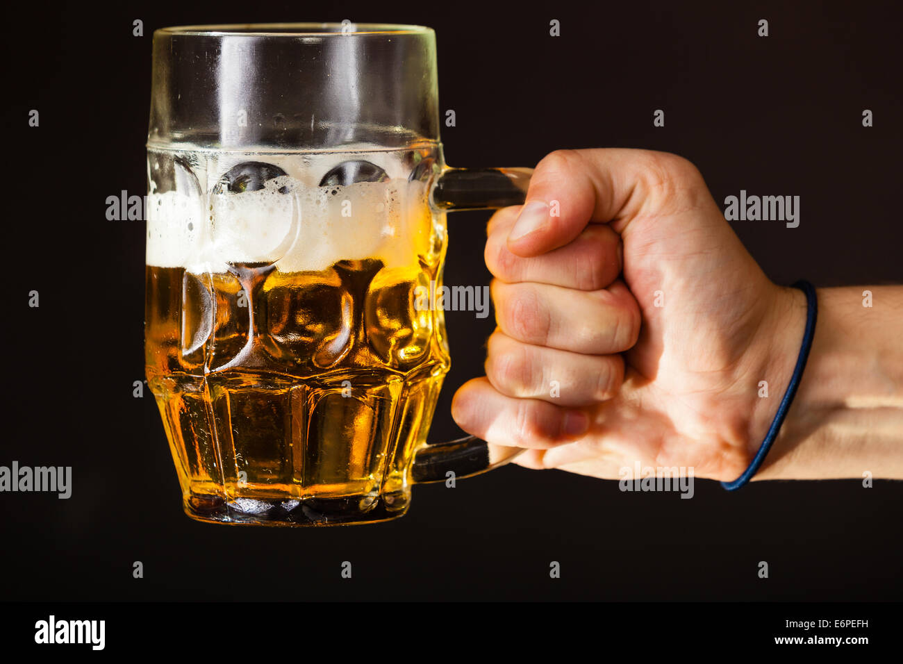 Male hand holding mug of beer dark background Stock Photo - Alamy