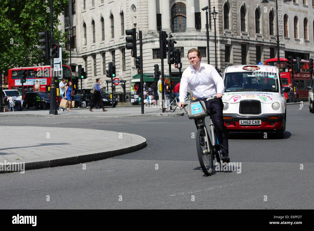A cyclist and a taxi traveling around a roundabout in Trafalgar Square ...