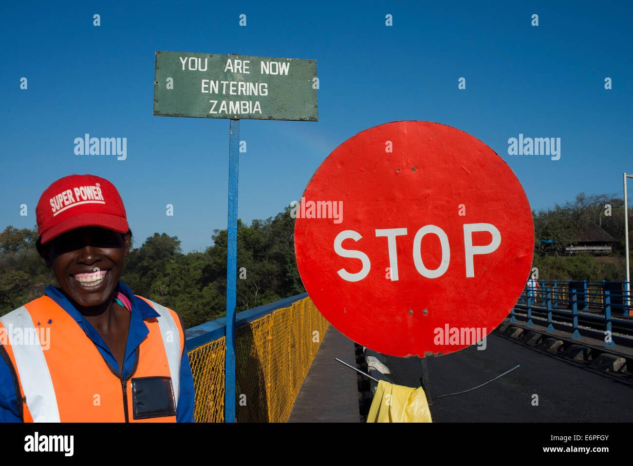 A woman controls the traffic between Zambia and Zimbabwe. A STOP sign ...