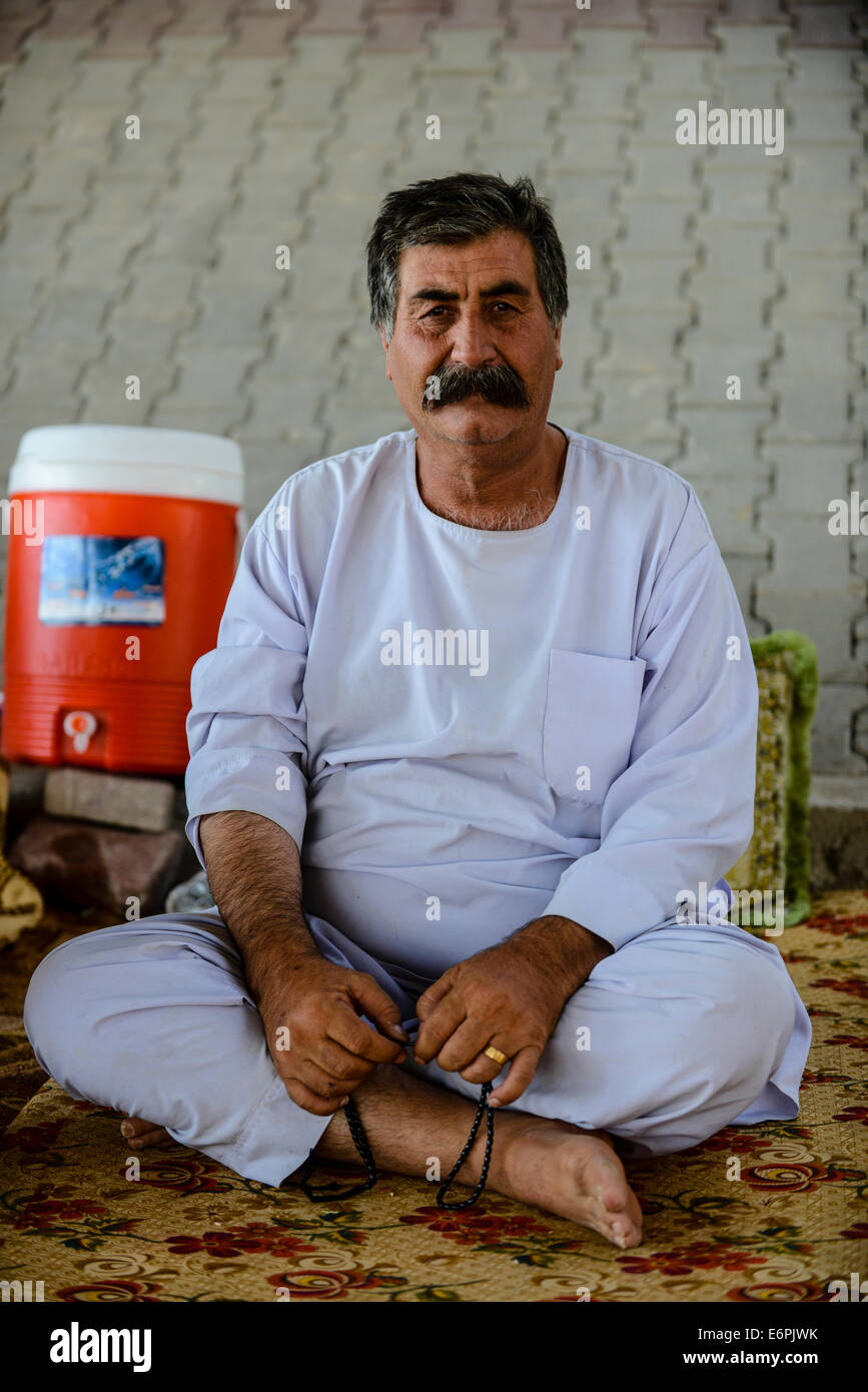 A Yezidi man sits beside the road. The Yezidi refugees live in an an ...
