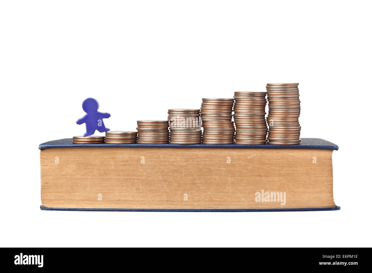 Figurine moving up stacks of money on top of a book isolated on white ...