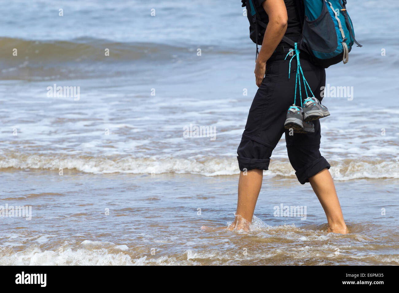 Female backpacker walking along the beach Stock Photo - Alamy