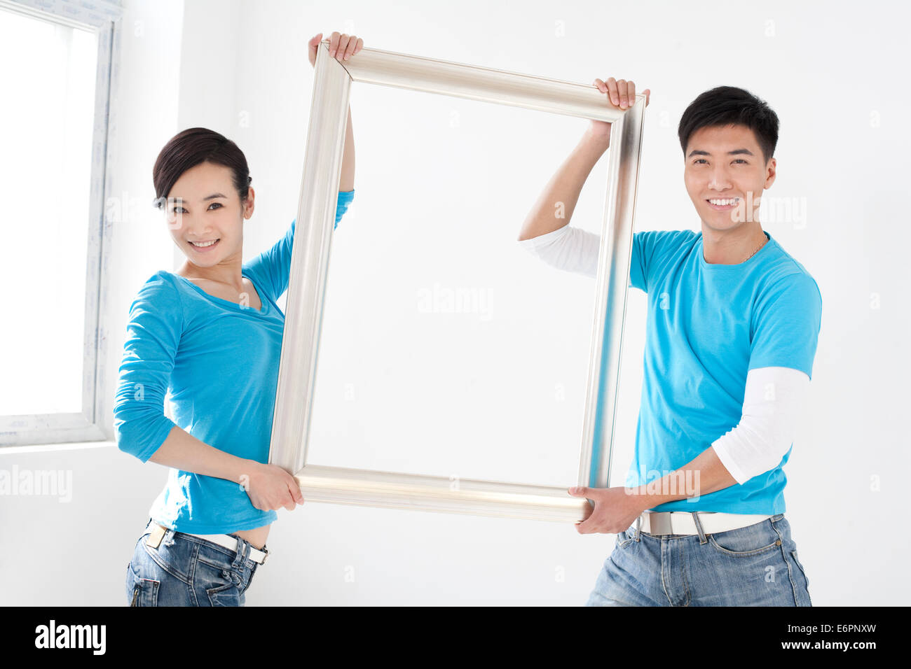 Happy couple holding up a picture frame Stock Photo - Alamy