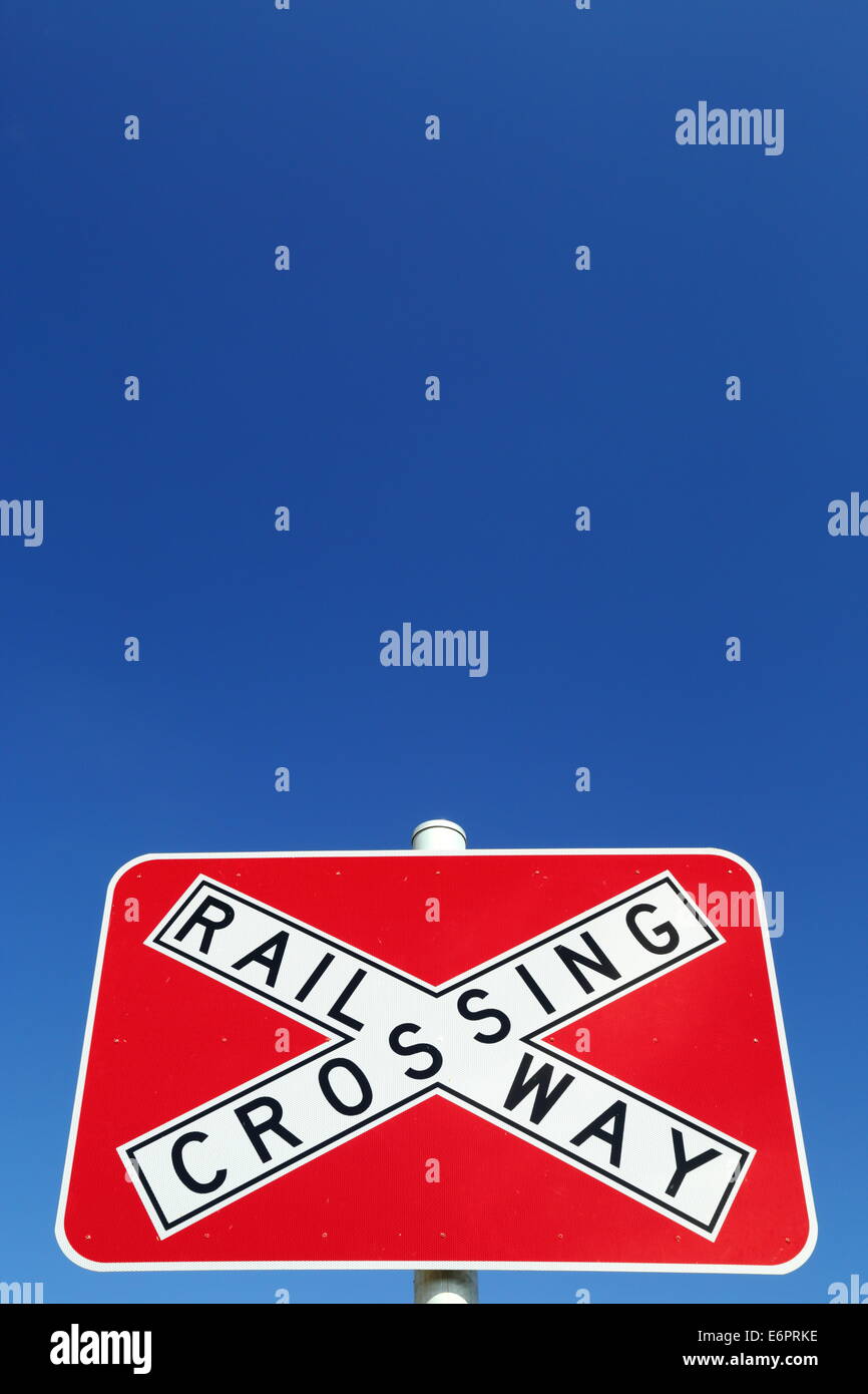A bright red sign along a country road warns drivers of a railway ...