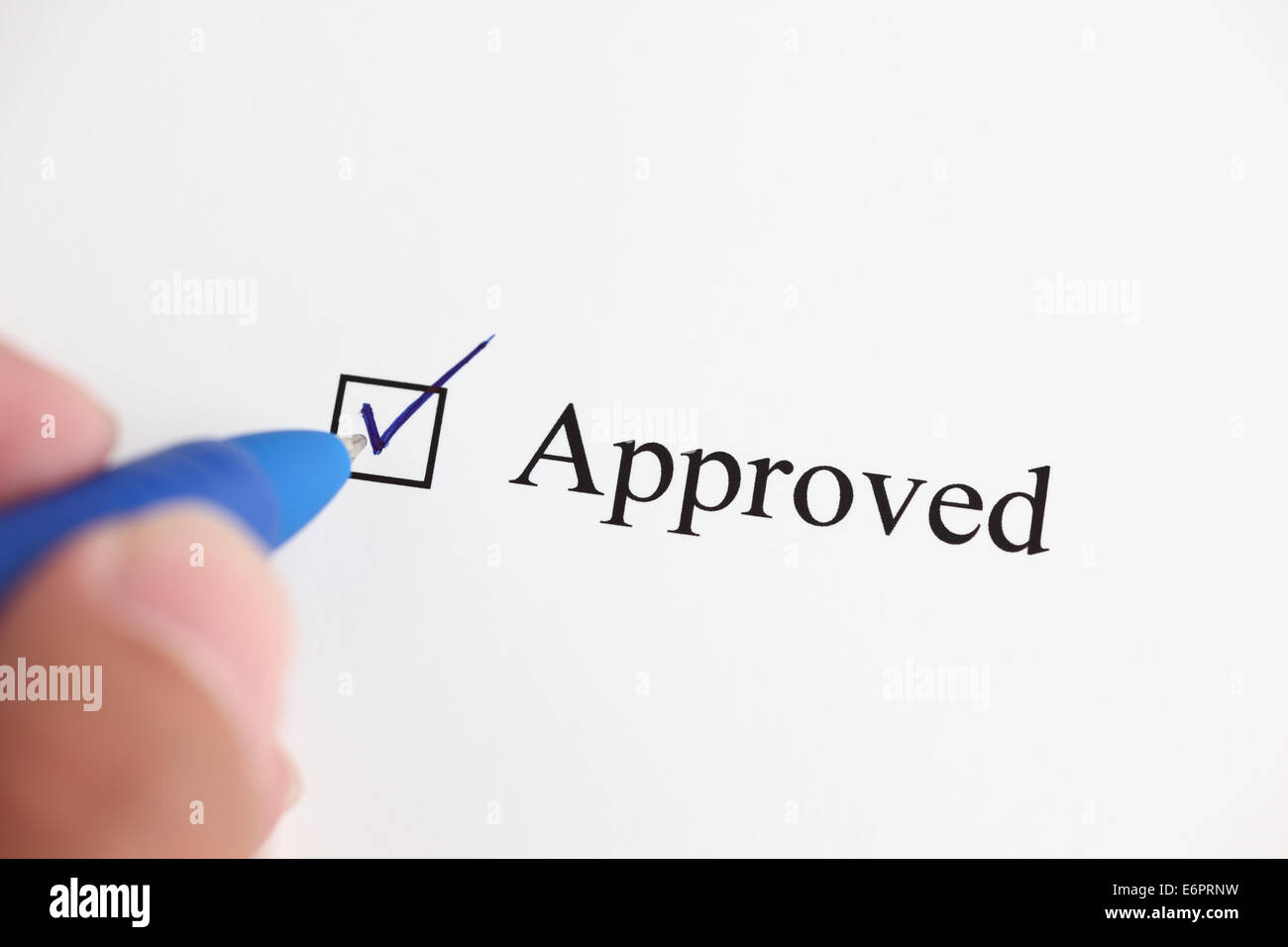 Hand with ballpoint pen marking the Approved checkbox on a document ...