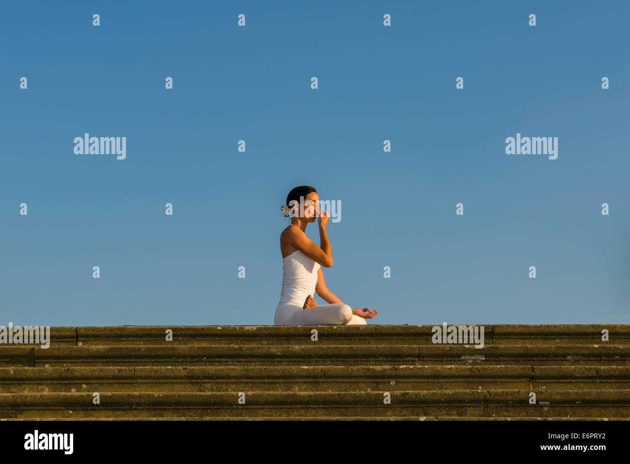 Young woman practising Hatha yoga, outdoors, showing the pose Anuloma ...