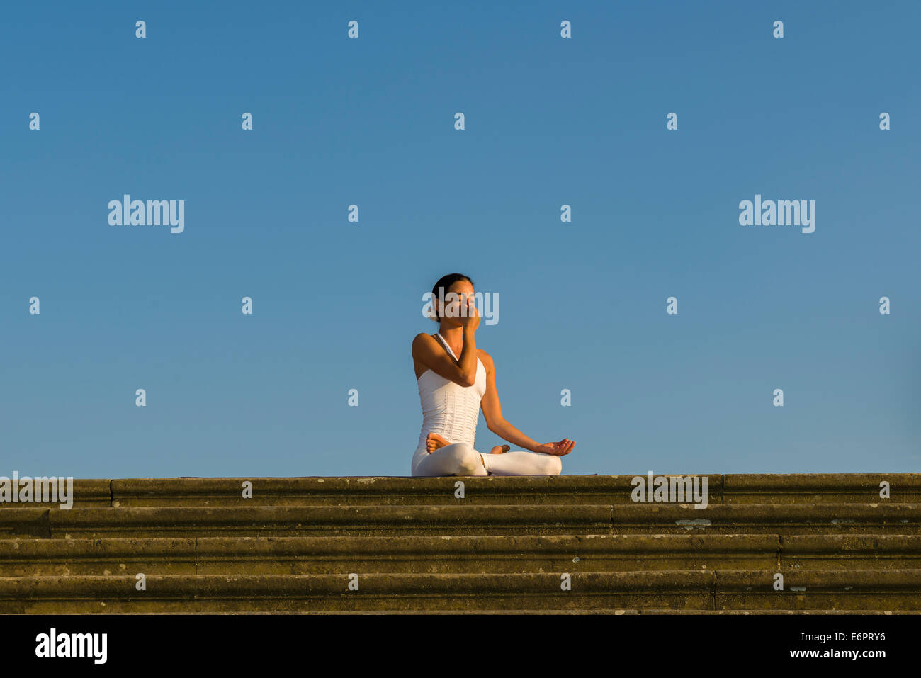Young woman practising Hatha yoga, outdoors, showing the pose Anuloma ...