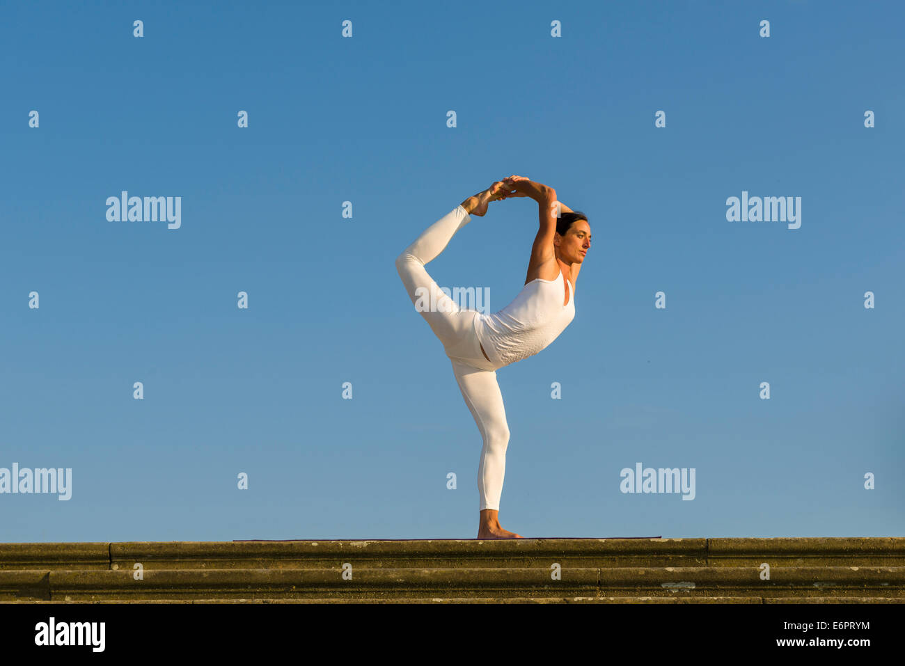 Young woman practising Hatha yoga, outdoors, showing the pose ...