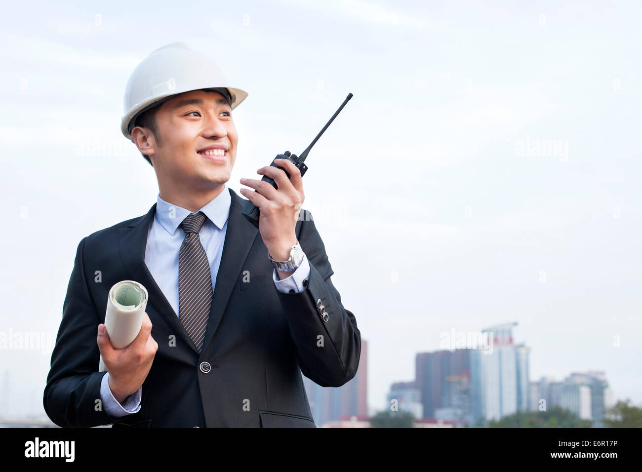 Young male architect with intercom and blueprint outdoors Stock Photo ...