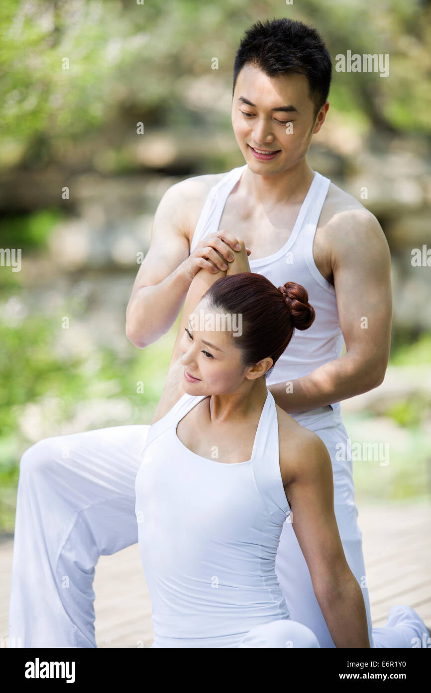 Young man teaching woman yoga Stock Photo - Alamy