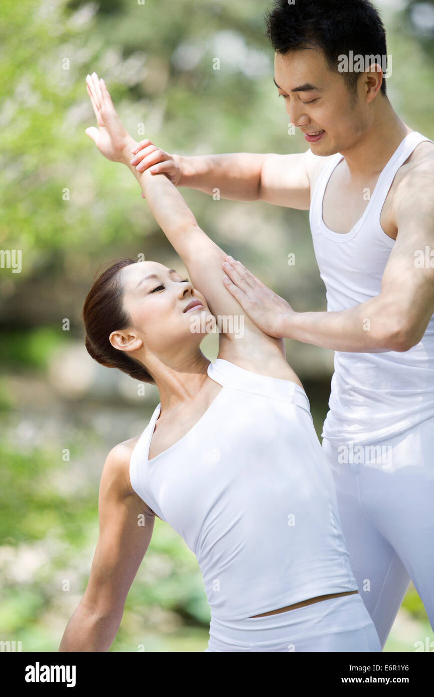 Young man teaching woman yoga Stock Photo - Alamy