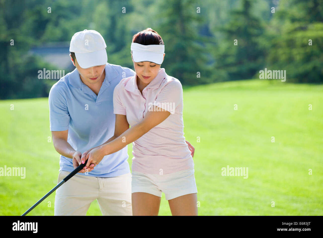 Young man teaching his girlfriend how to play golf Stock Photo - Alamy