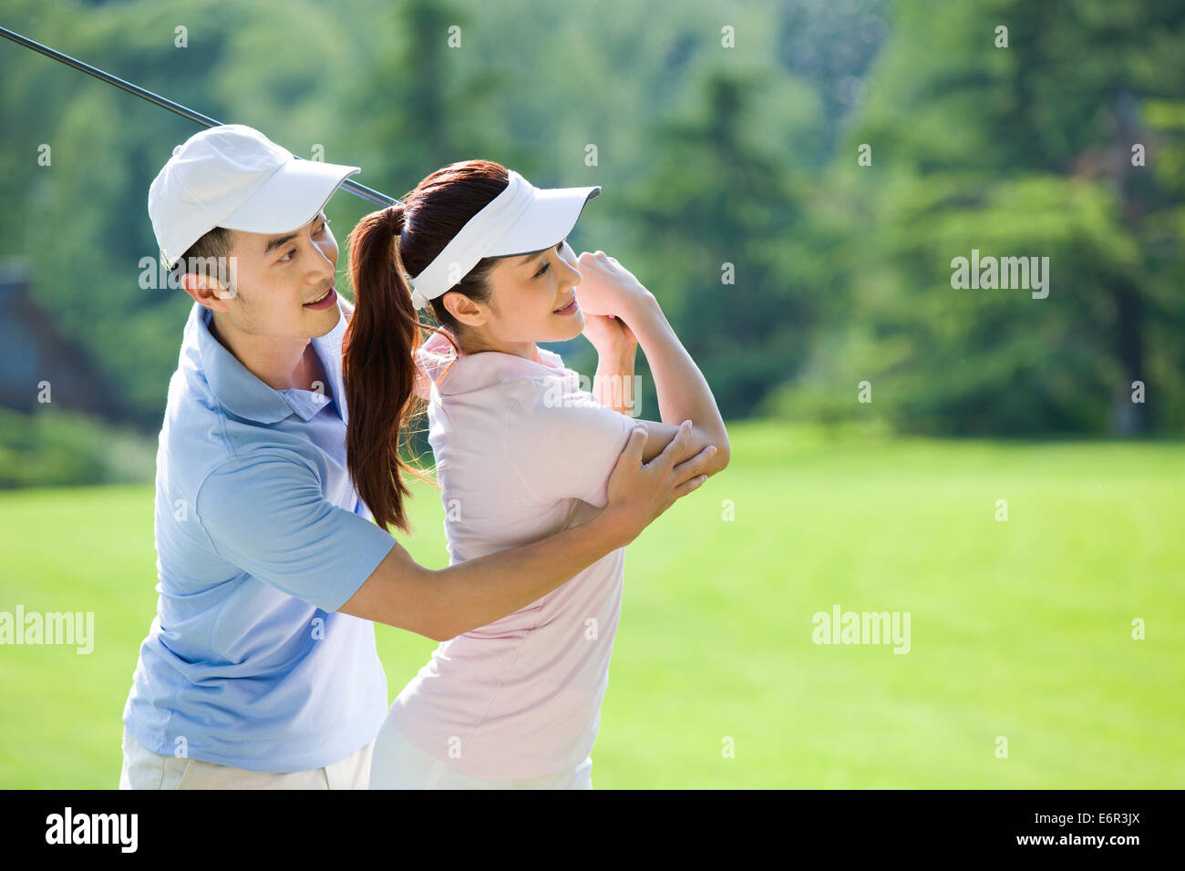 Young man teaching his girlfriend how to play golf Stock Photo - Alamy