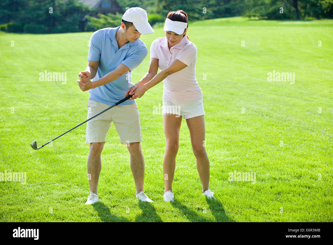 Young man teaching his girlfriend how to play golf Stock Photo - Alamy