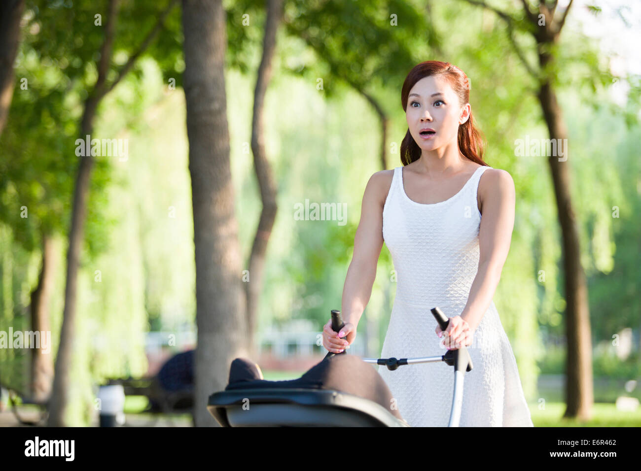 Young woman pushing a pram with shocked expression Stock Photo - Alamy