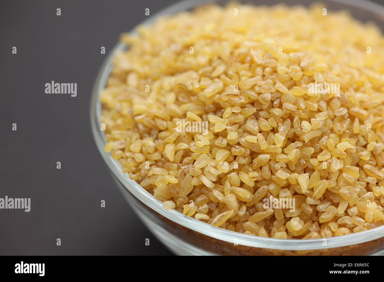 Bulgur wheat in a glass bowl on black background Stock Photo - Alamy