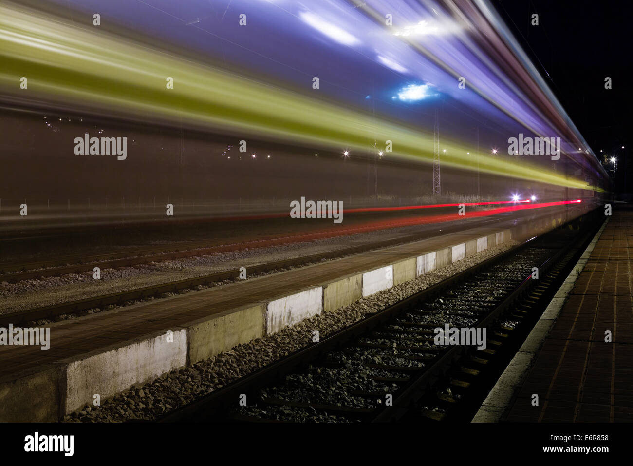 Red and blue train leaving a small roofless dutch train station at ...