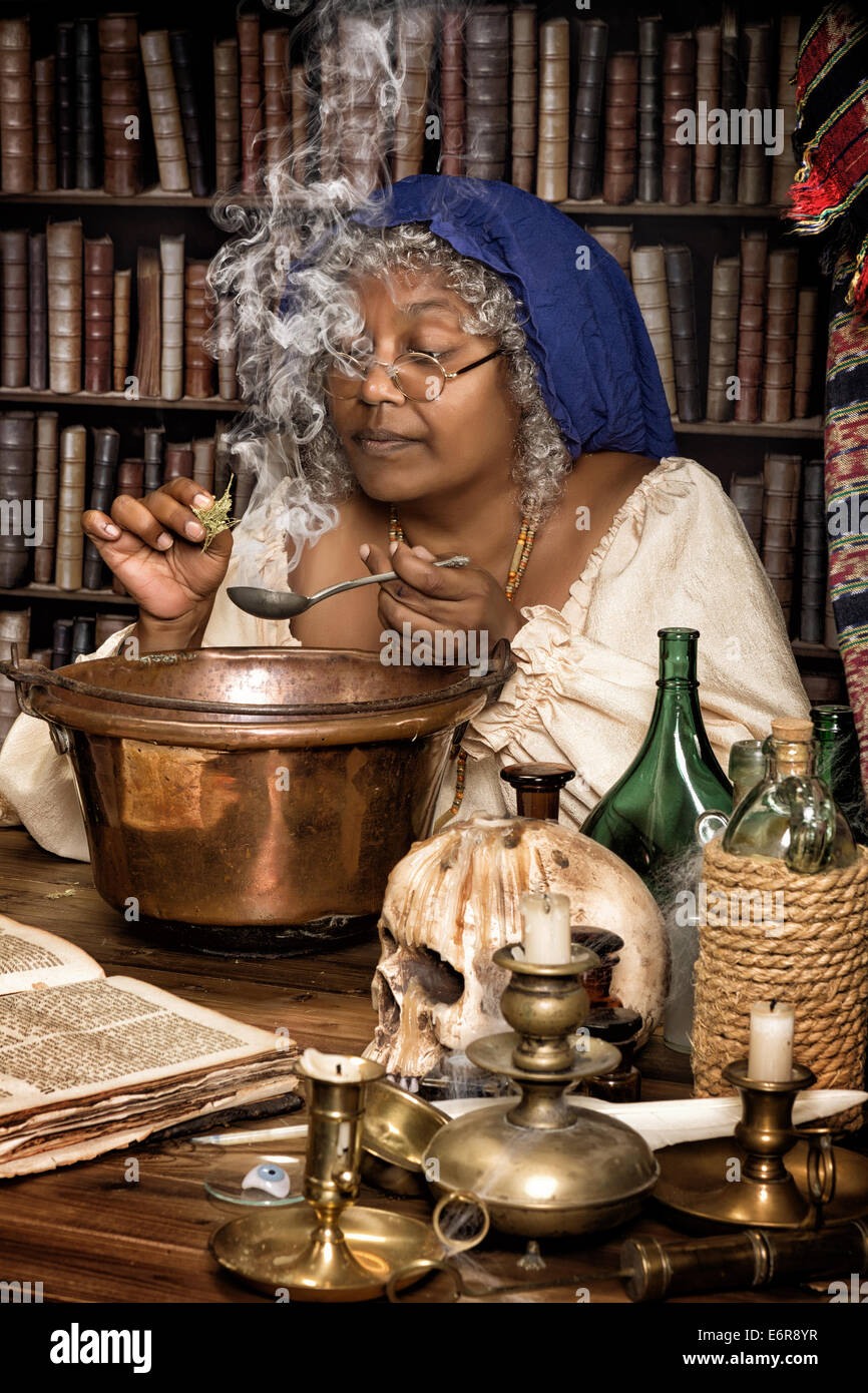 Vintage alchemist adding herbs to a smoking kettle Stock Photo - Alamy