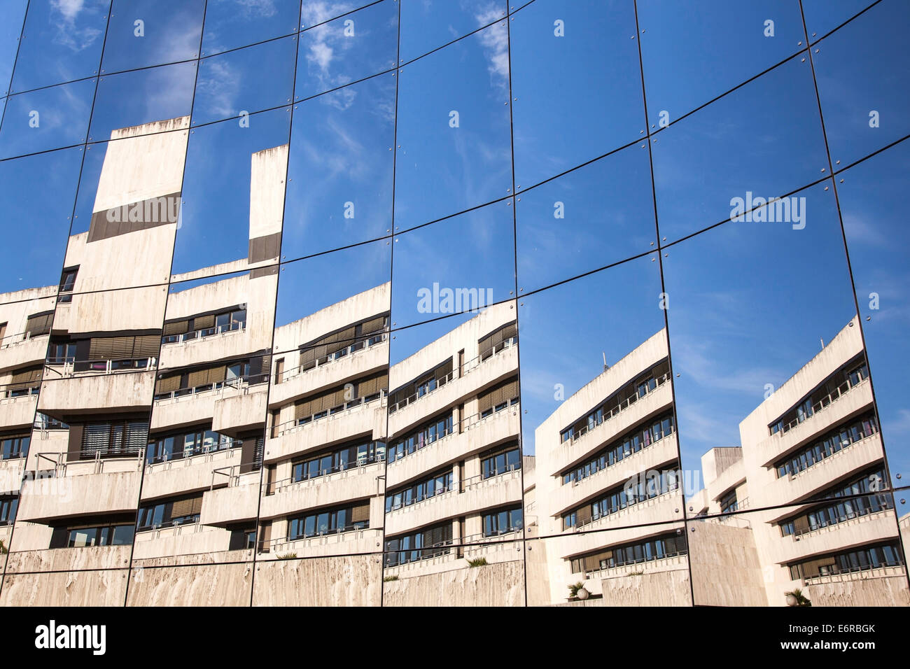 glass panes on facade of trade building reflecting blue sky and another ...