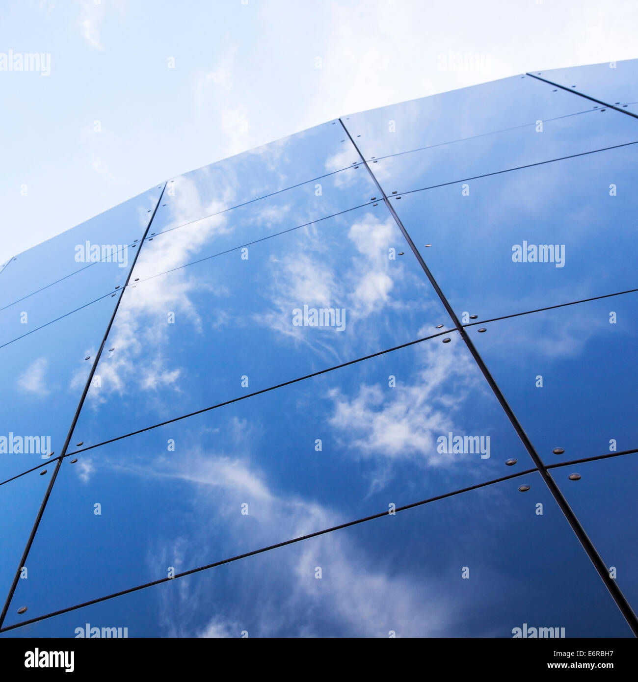 glass panes on facade of trade building reflecting blue sky and clouds ...