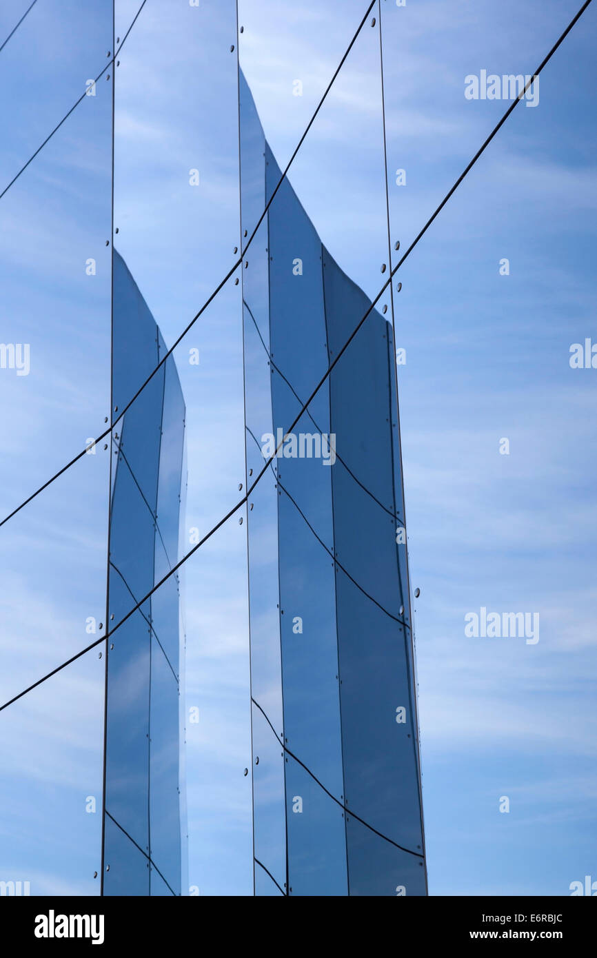 glass panes on facade of trade building reflecting blue sky and clouds ...