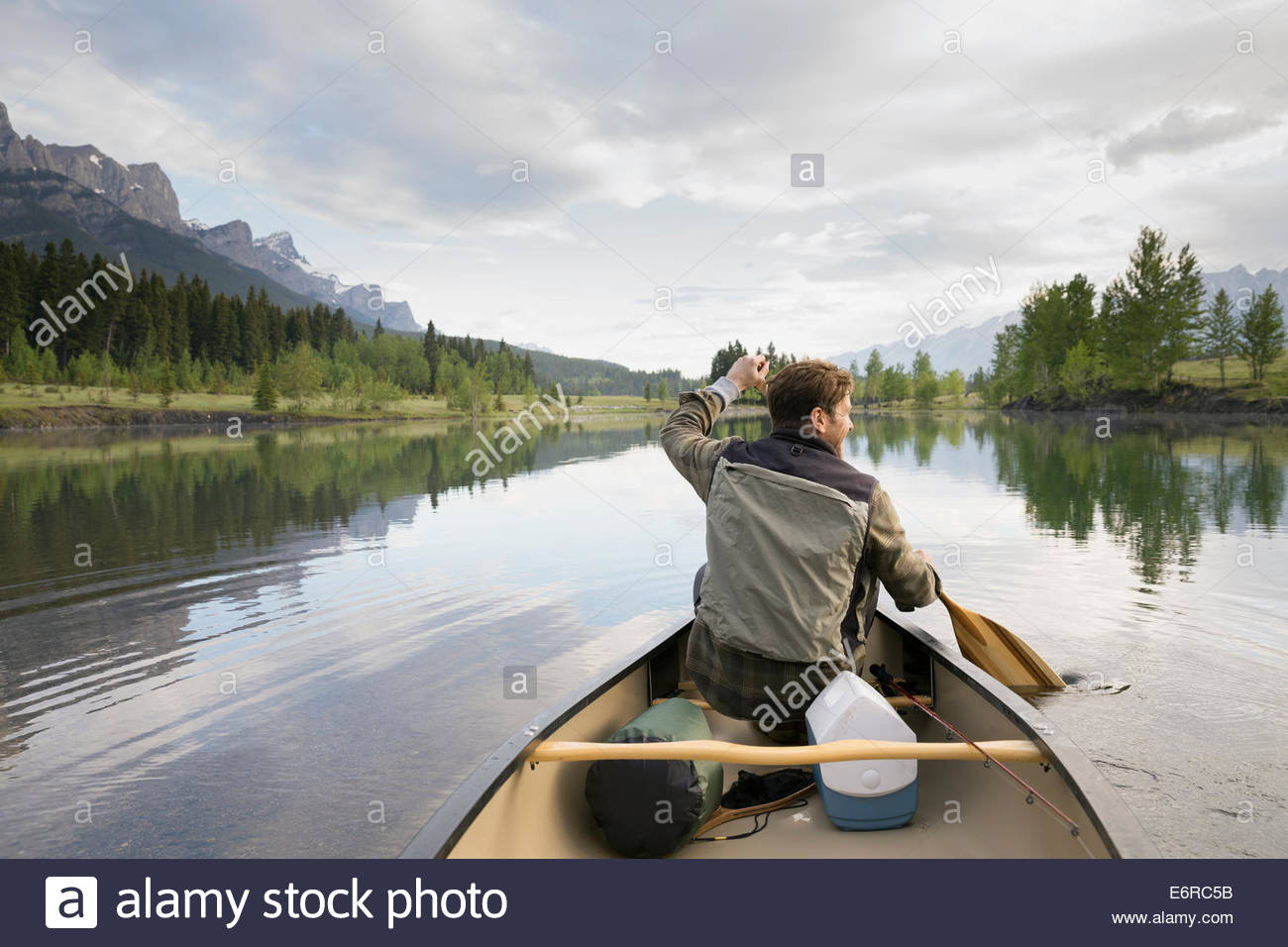 Man rowing canoe in still lake Stock Photo - Alamy
