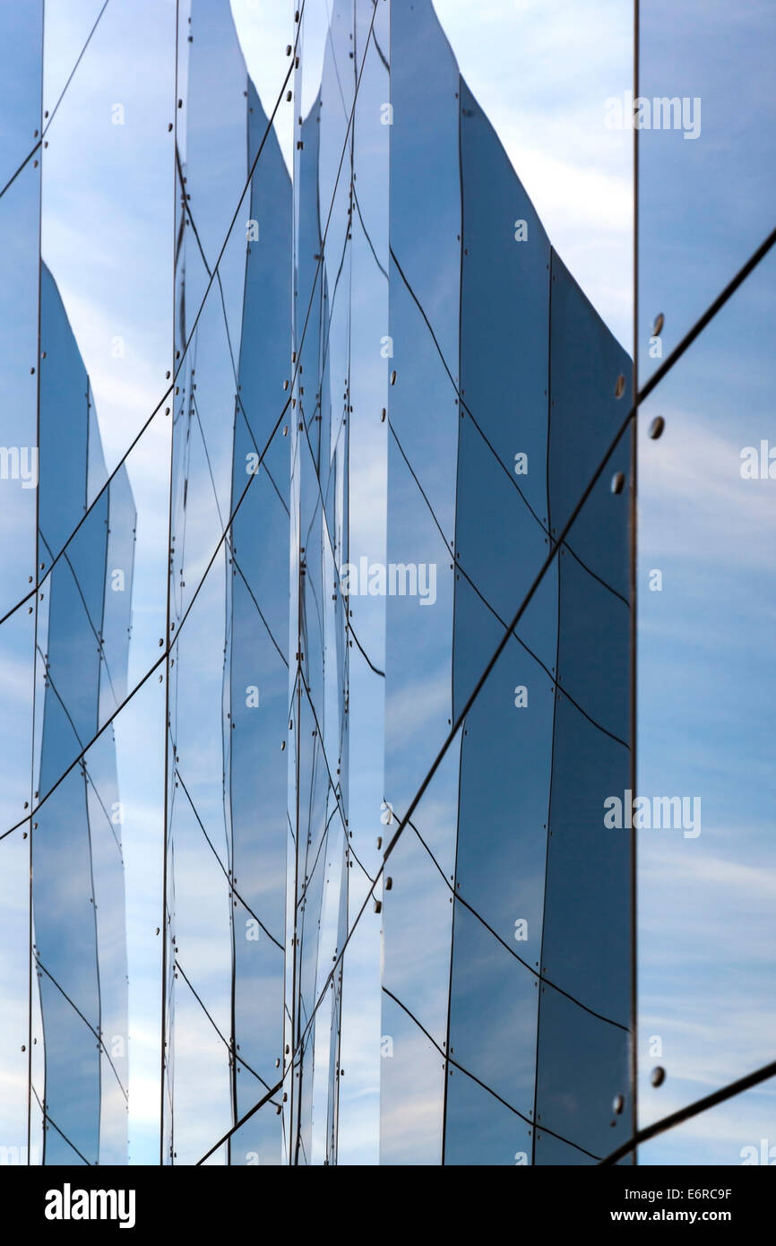 glass panes on facade of trade building reflecting blue sky and another ...