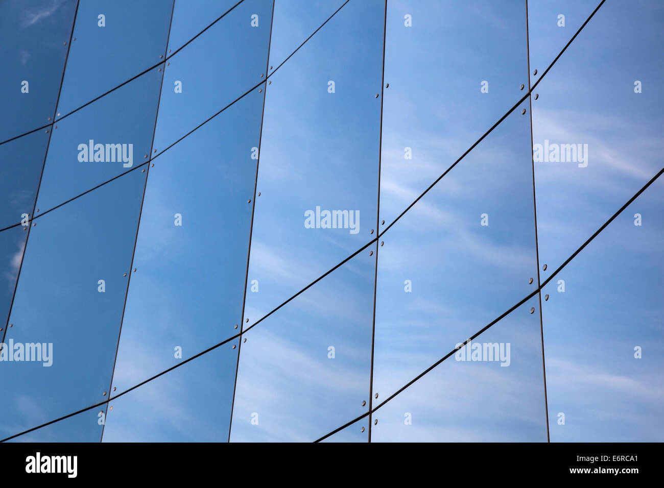 glass panes on curved facade of trade building reflecting blue sky and ...